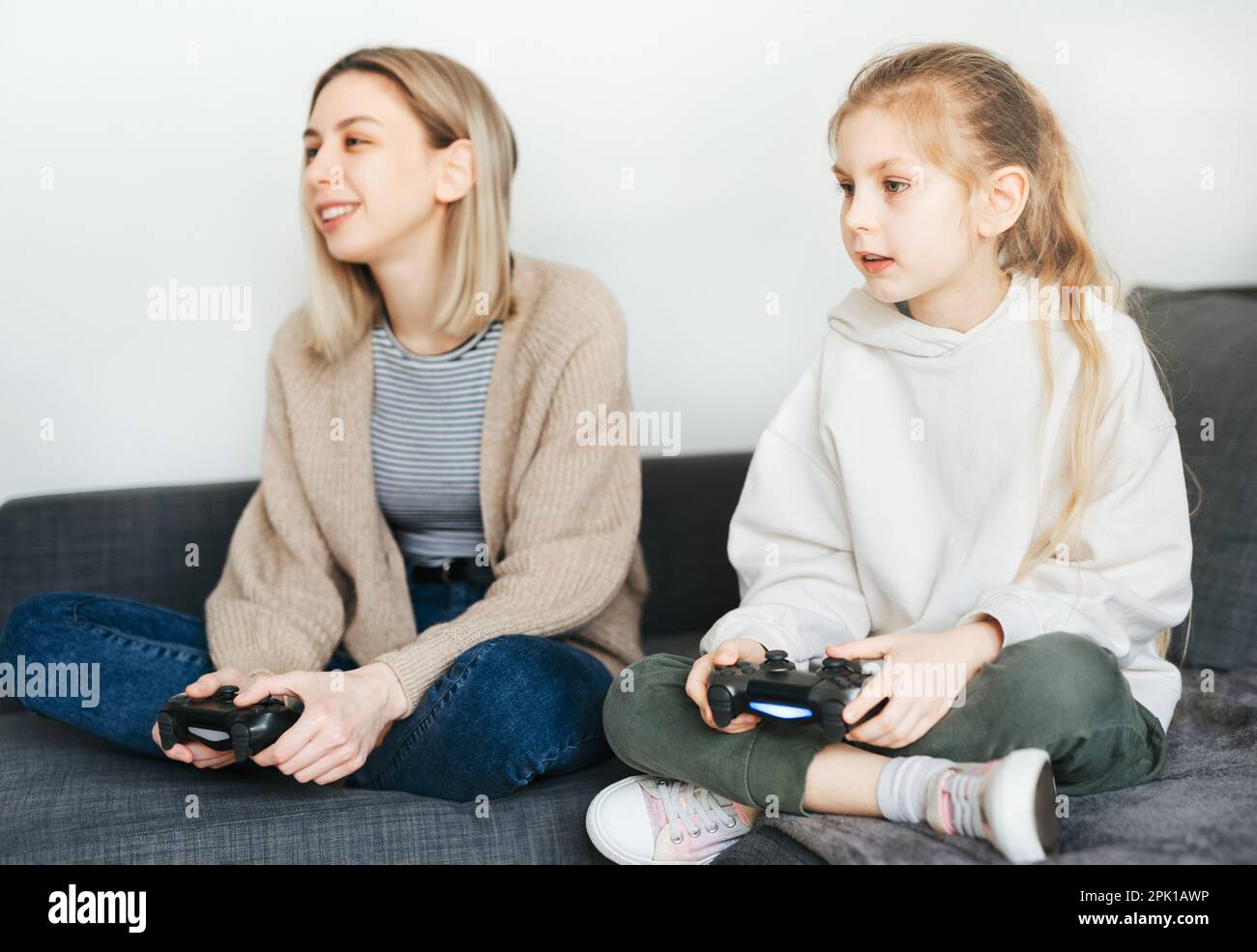 Young women and little girl joyful playing video games with controller ...