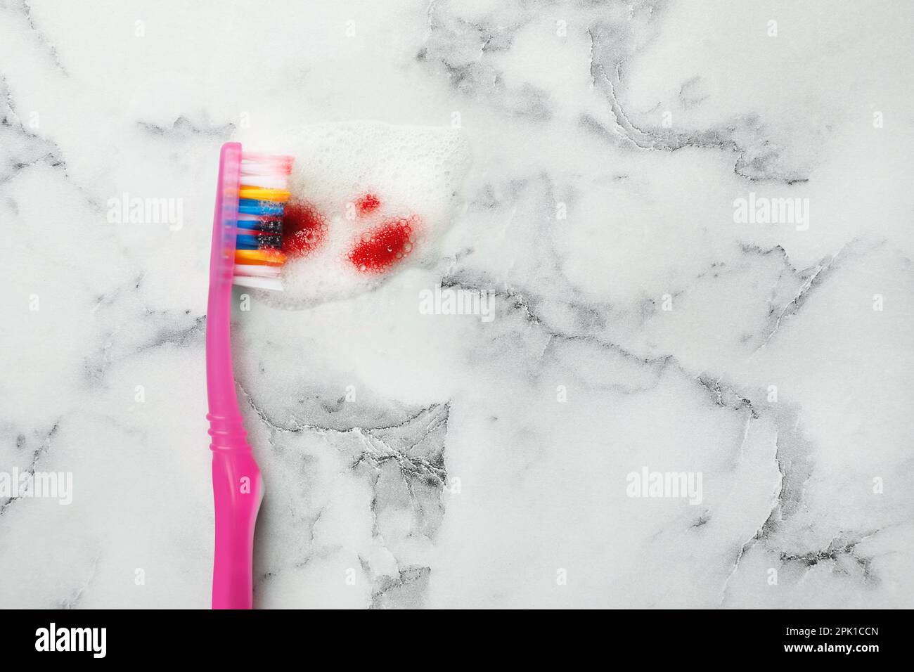 Brush, toothpaste foam with blood on white marble table, top view and ...