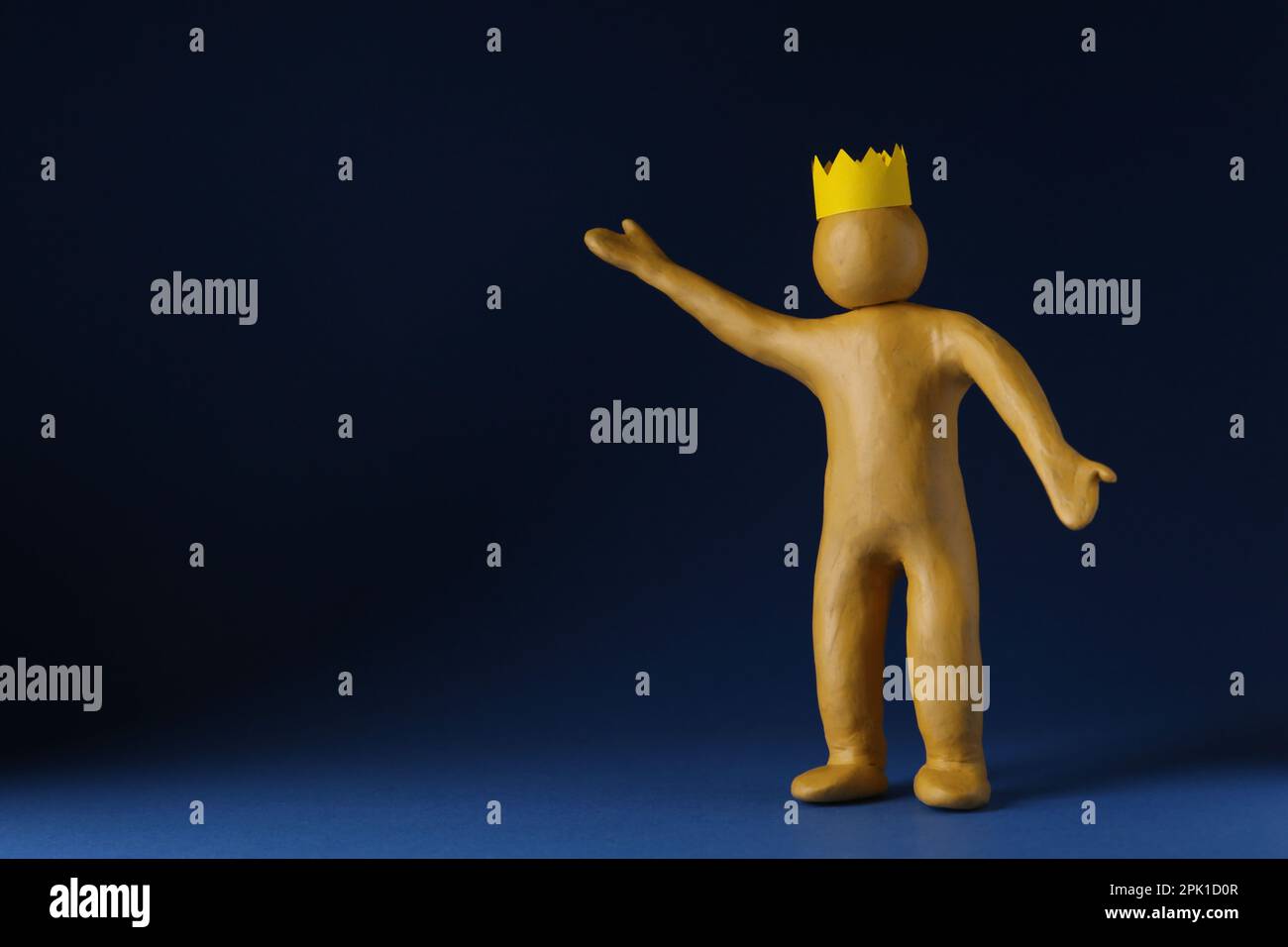 Plasticine figure with crown on head against dark blue background ...