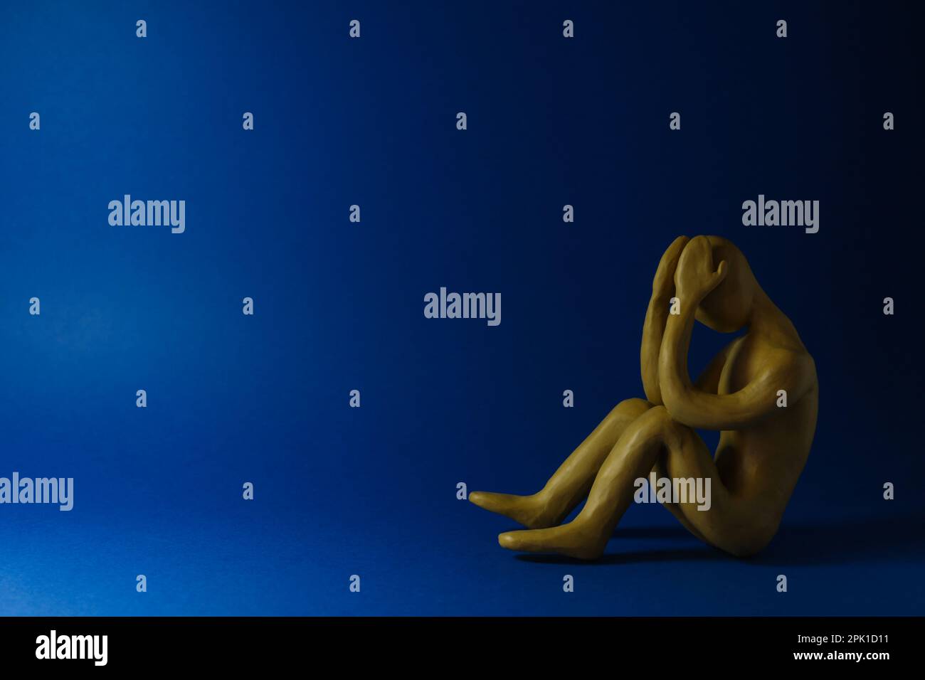 Plasticine figure of crying human on dark blue background. Space for ...