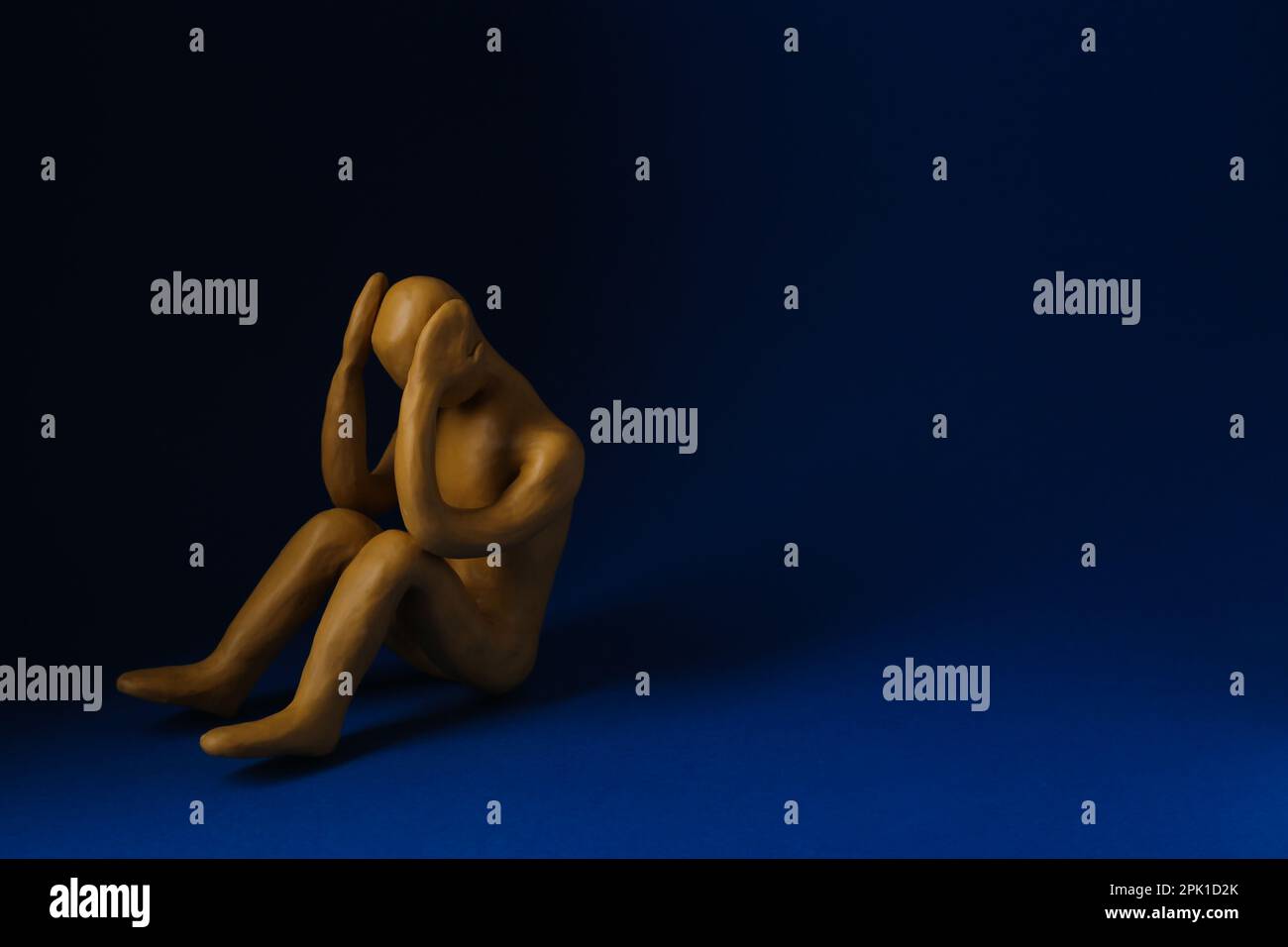 Plasticine figure of crying human on dark blue background. Space for ...