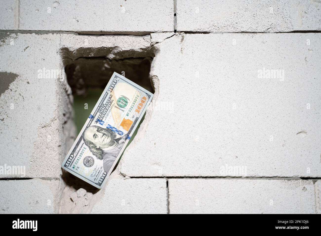 A hundred dollar bill lies in a through hole in a wall of aerated ...
