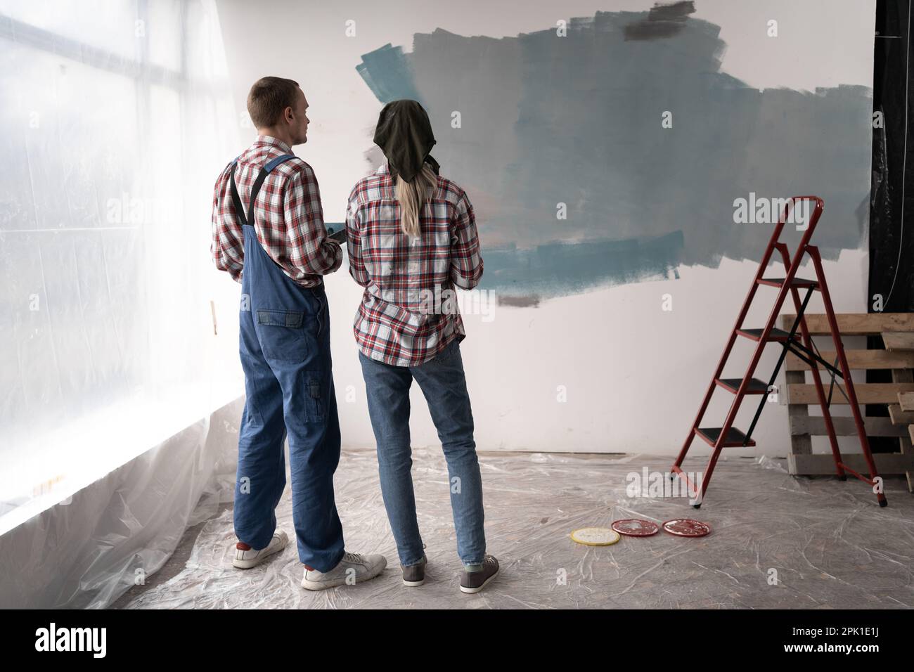 Young loving couple staring at their painted room, back view. Home ...