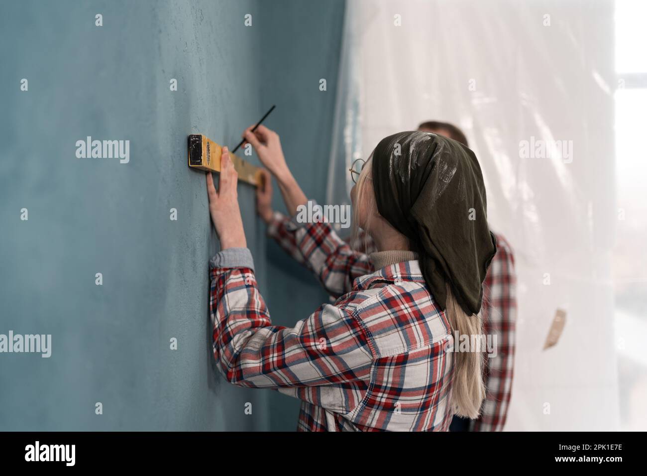 Happy couple building new home measuring wall using spirit level to ...