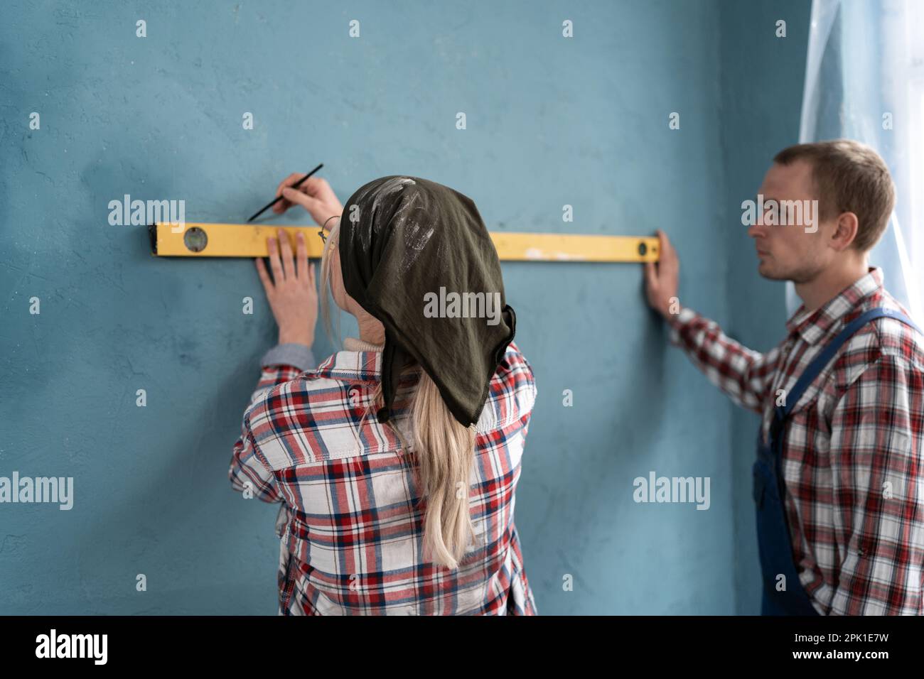Happy couple building new home measuring wall using spirit level to ...