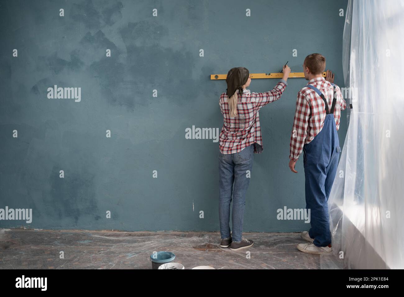 Repair home concept. A young couple are measuring a wall with spirit ...