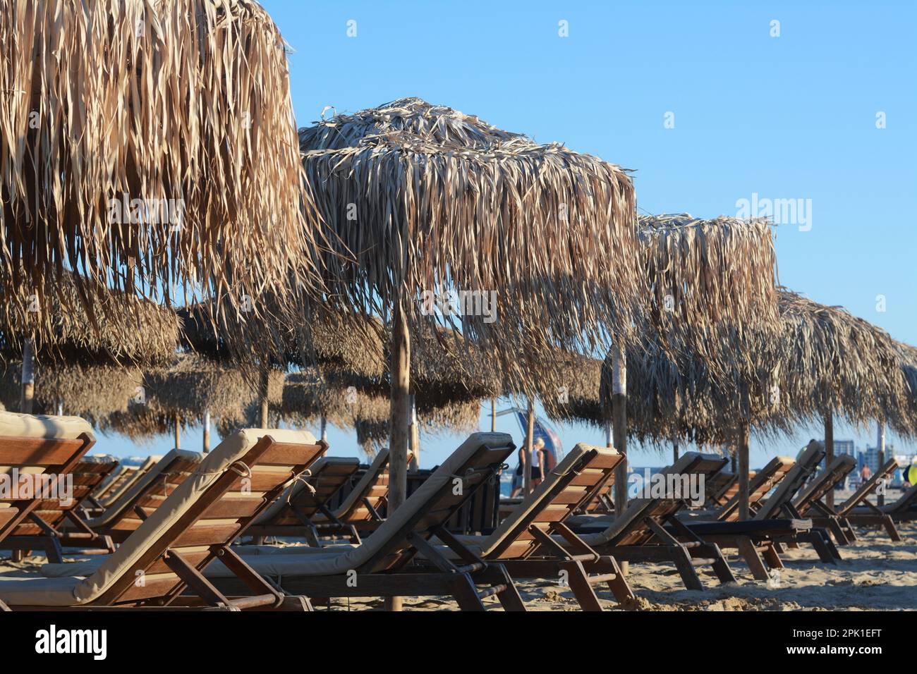 Beautiful straw umbrellas and wooden sunbeds on beach Stock Photo - Alamy