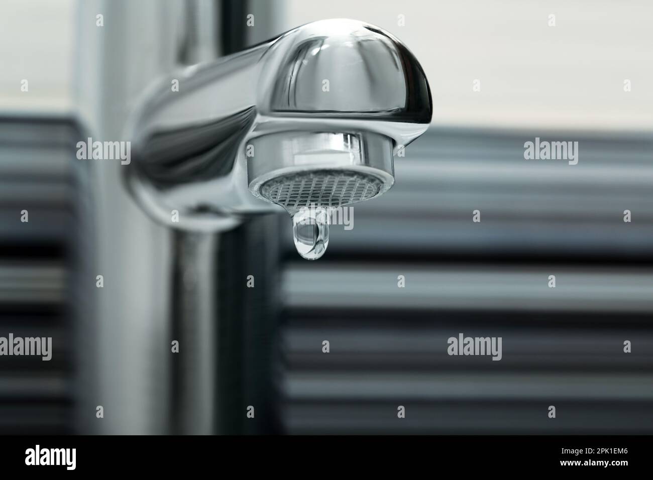 Water drop falling down from tap on blurred background, closeup. Space ...