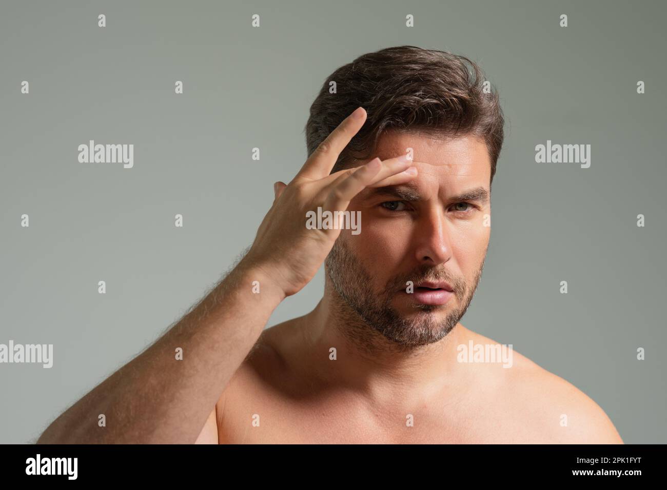 Close-up portrait of perfect brunet man touching chin and skin. Handsome man touching face in ...