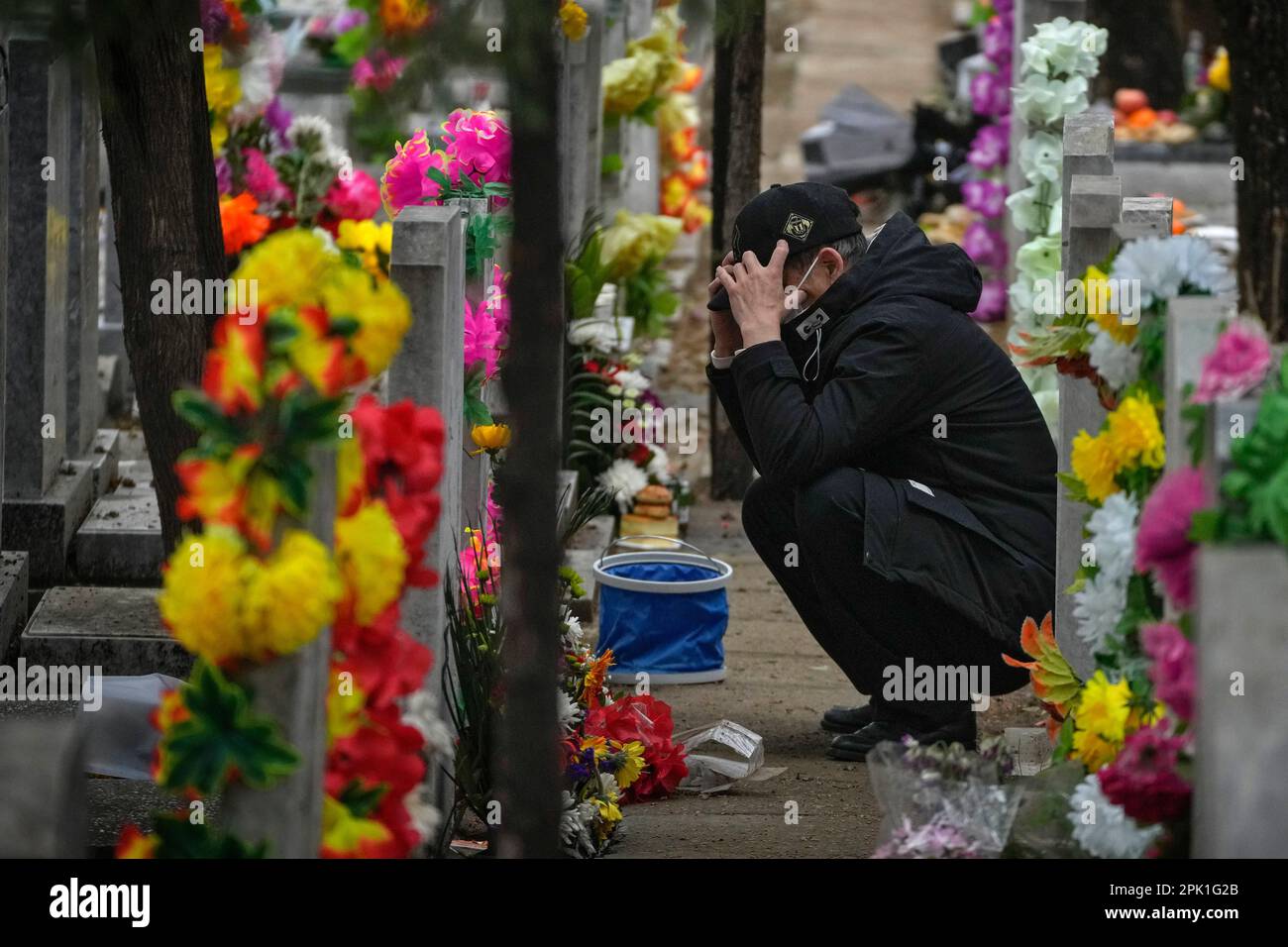 A resident reacts in front of a tomb during Qingming festival, also ...