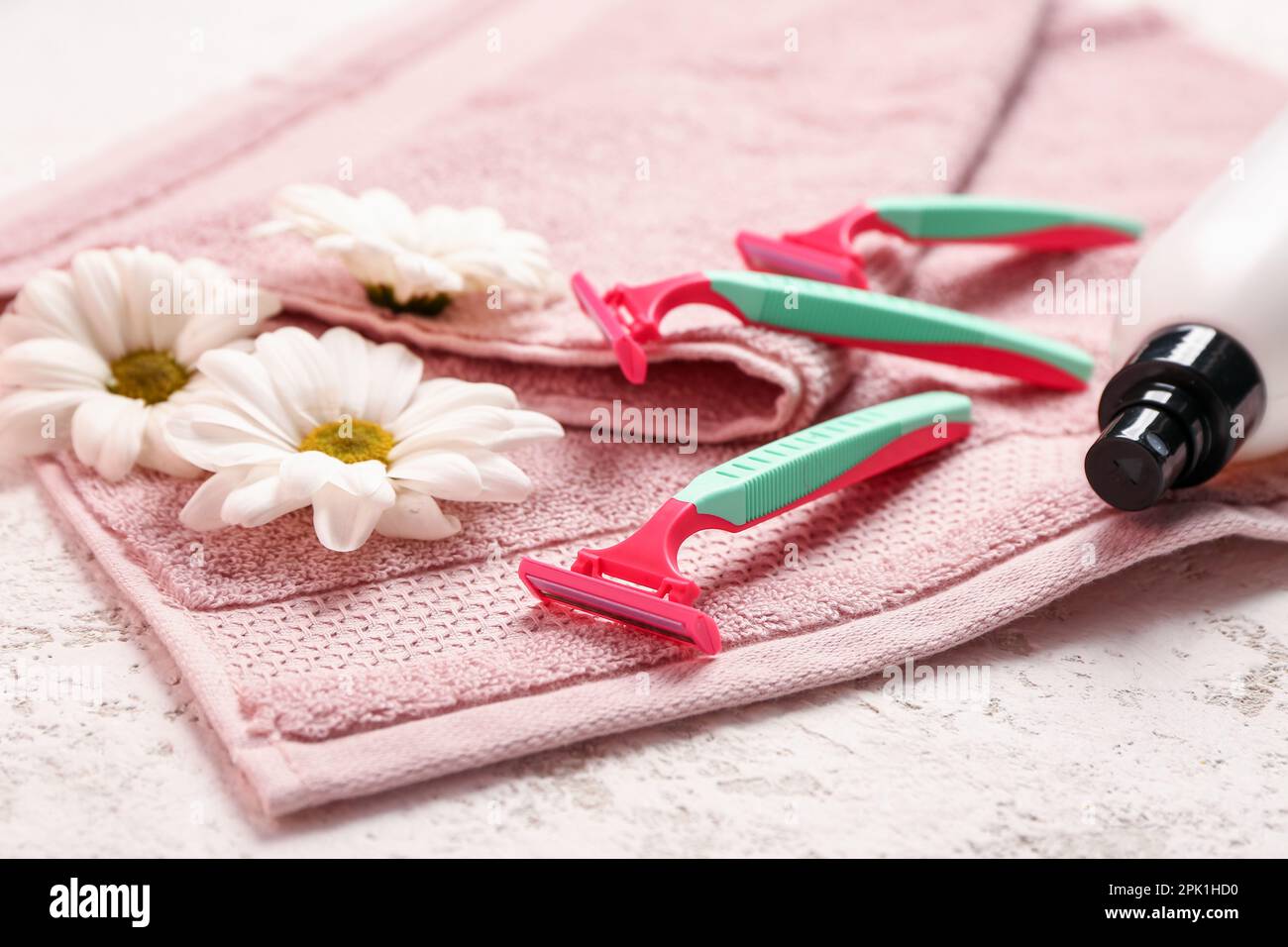 Safety razors, daisy flowers and towel on white grunge background Stock ...