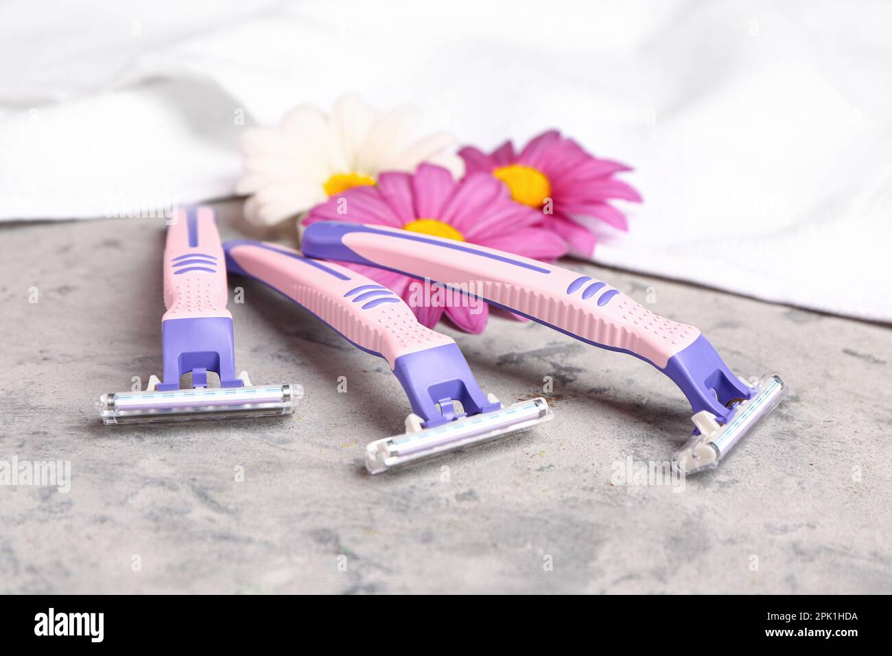 Safety razors, daisy flowers and towel on grey grunge background Stock ...