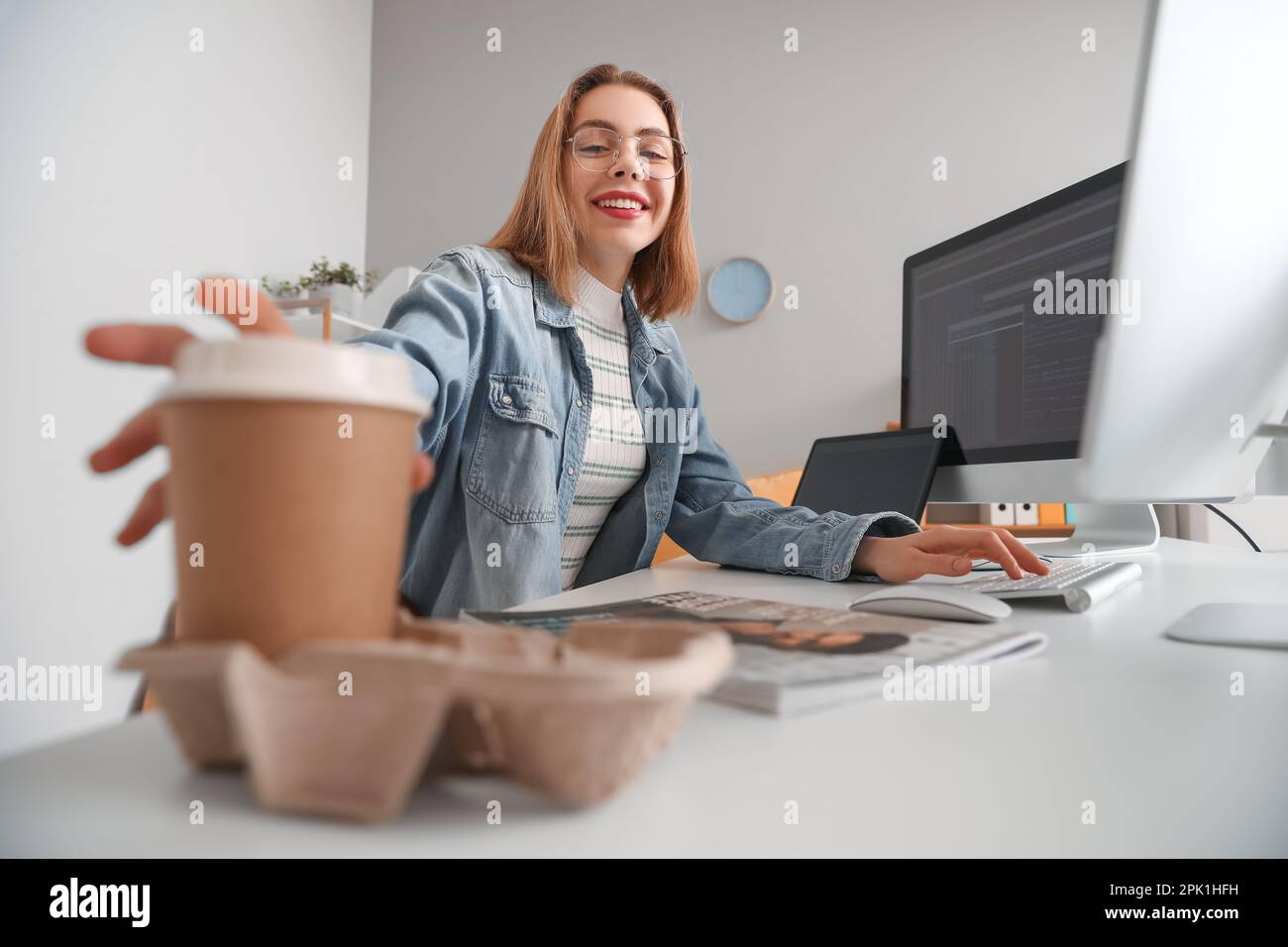 Female programmer taking cup of coffee from table in office Stock Photo ...