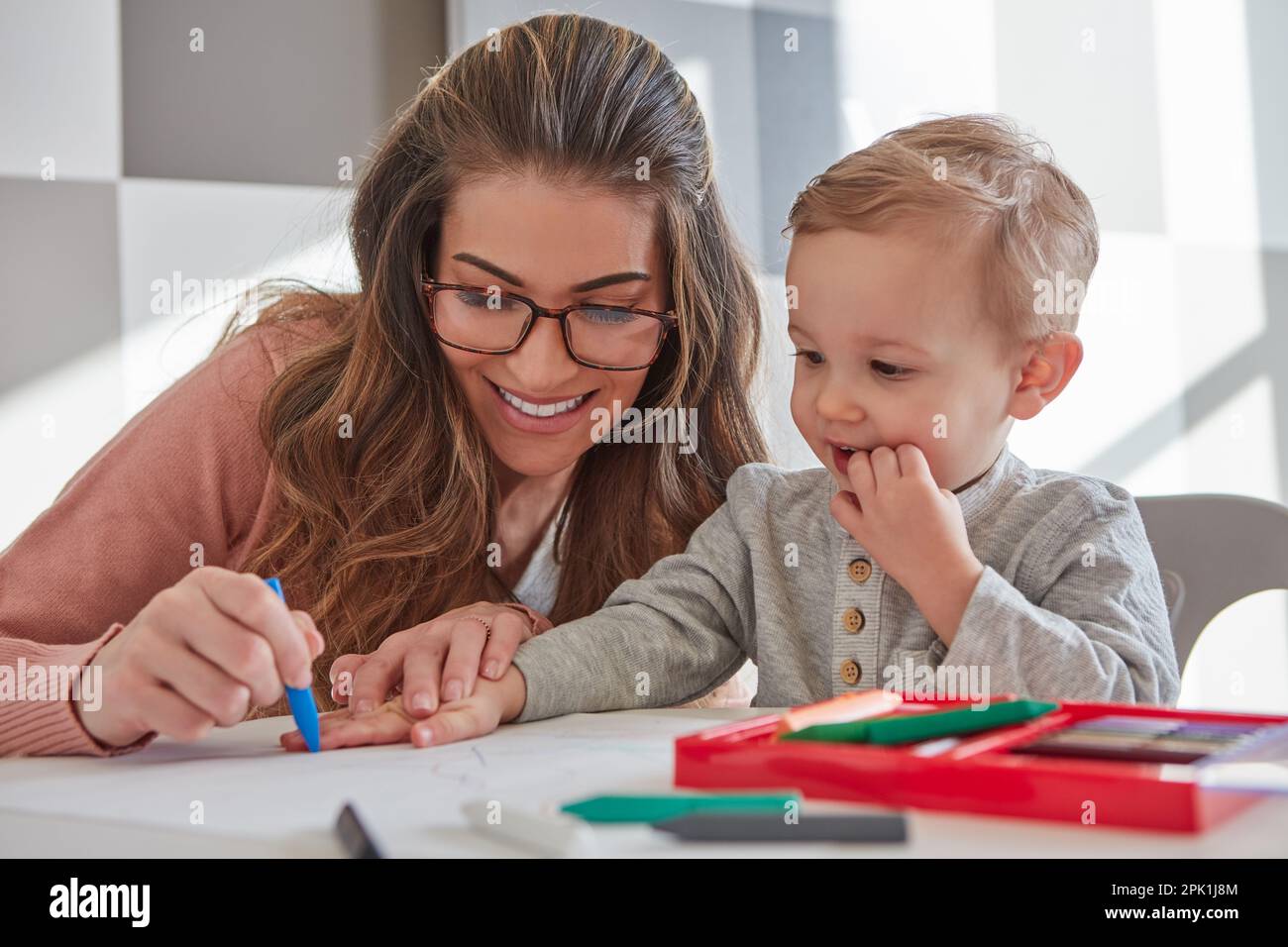 Watch me draw your hand...a woman and her young son using crayons to ...
