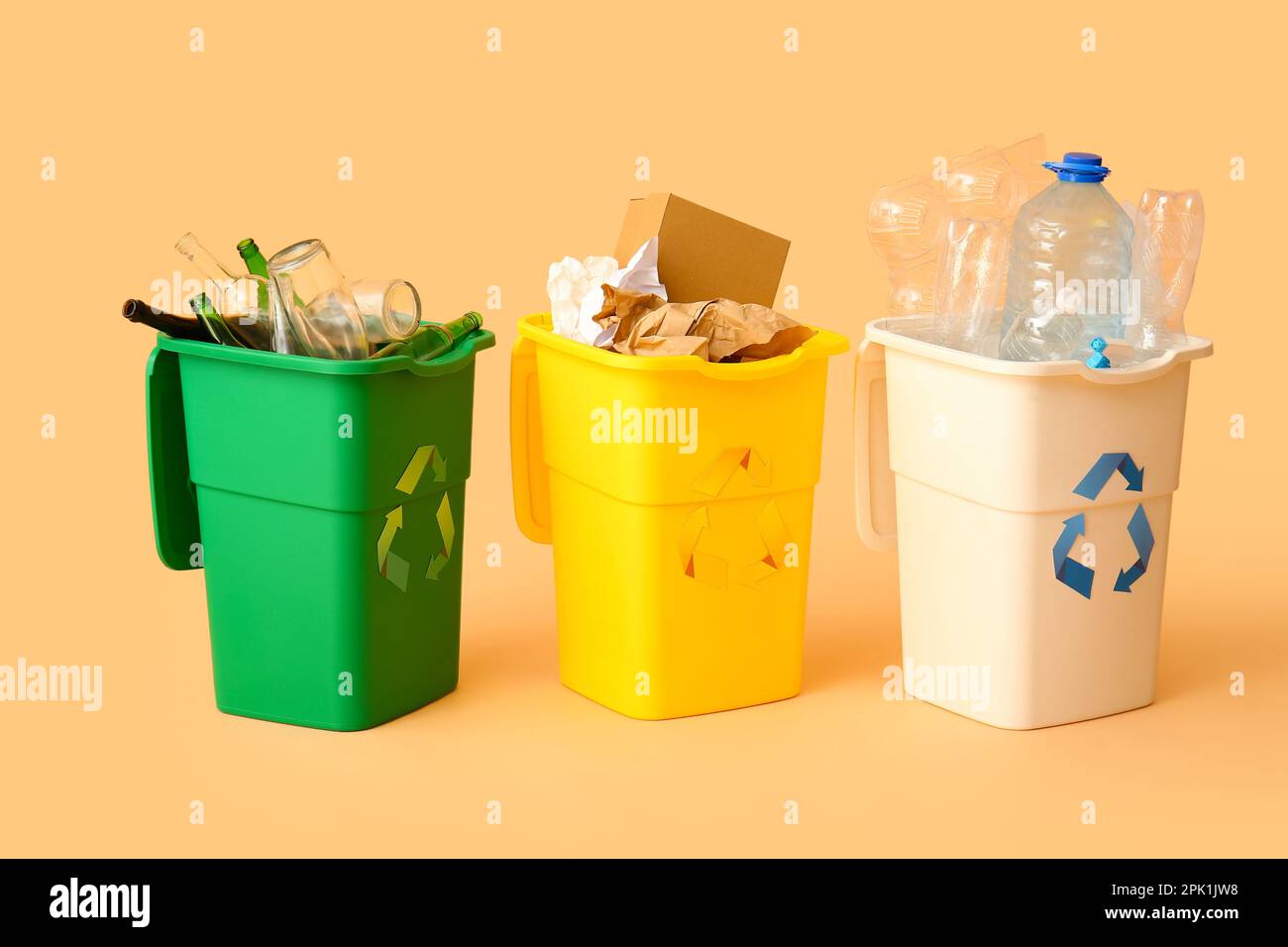 Containers with different types of garbage on beige background ...