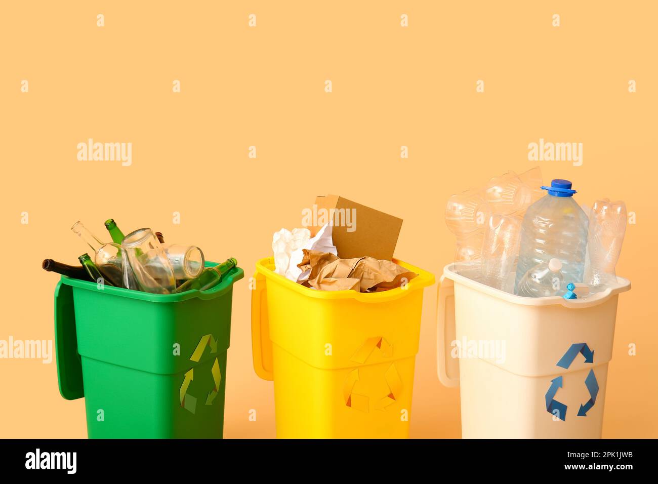 Containers with different types of garbage on beige background ...
