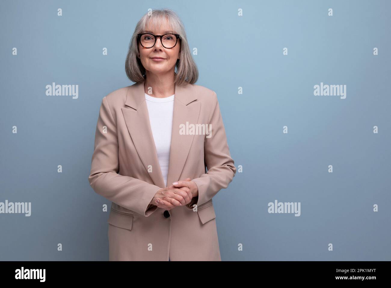 mature old woman in a stylish jacket posing against a bright studio ...