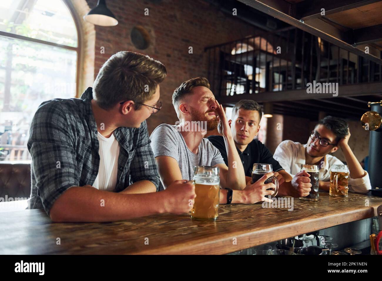 Side view of friends with beer. People in casual clothes sitting in the ...