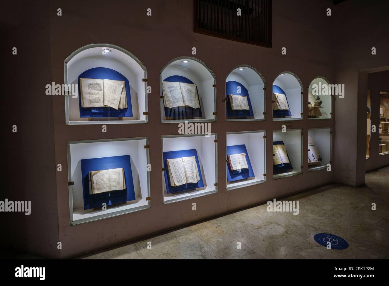 A museum display of old korans with arabic script, writing. At the ...