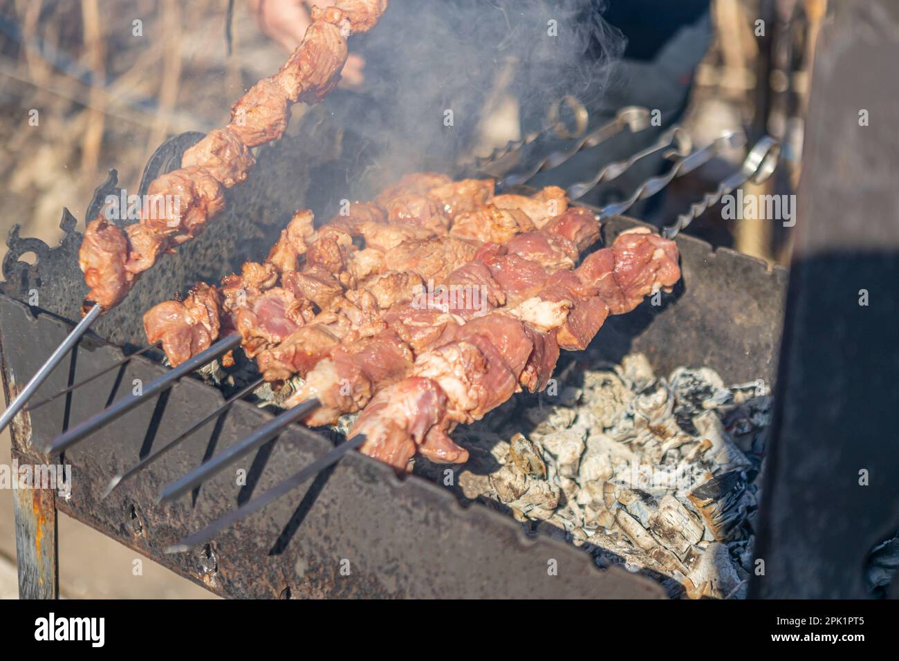 Grilled kebab cooking on metal skewer. Roasted meat cooked at barbecue ...