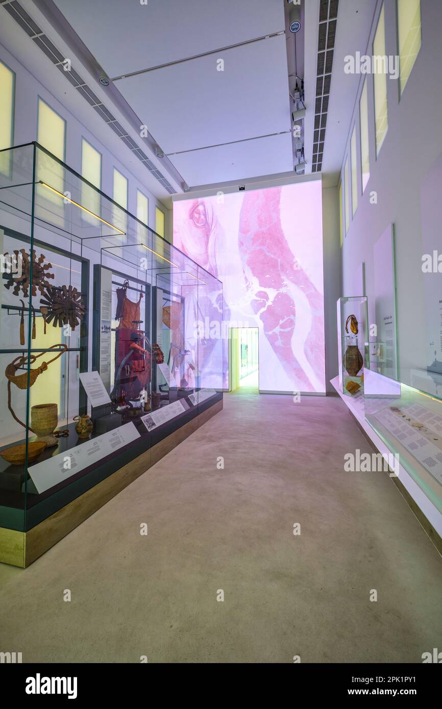 A large video plays in a room that displays old textiles and artifacts ...