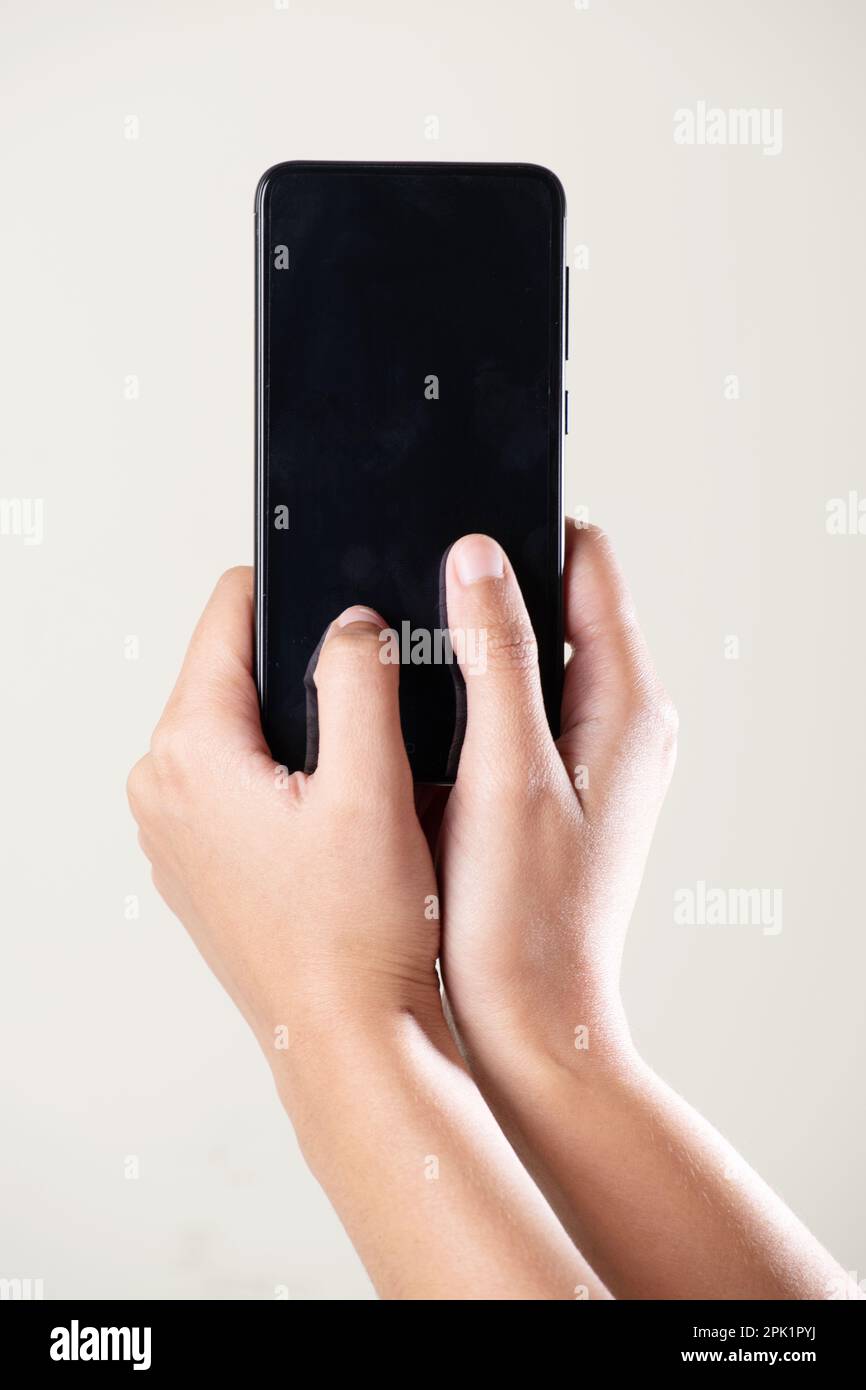 Smartphone vertical hold from both hands on grey background Stock Photo ...