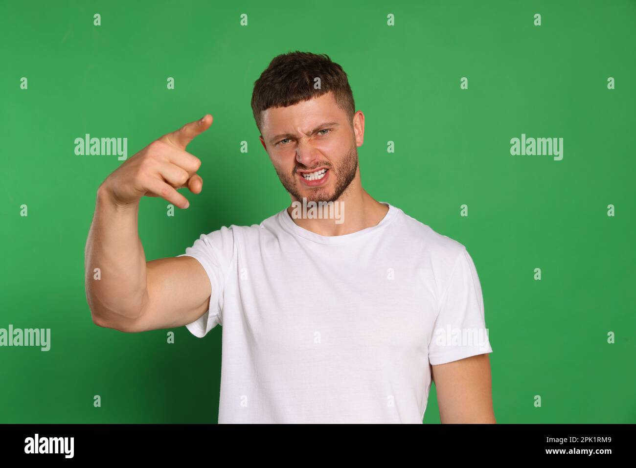 Aggressive young man pointing on green background Stock Photo - Alamy