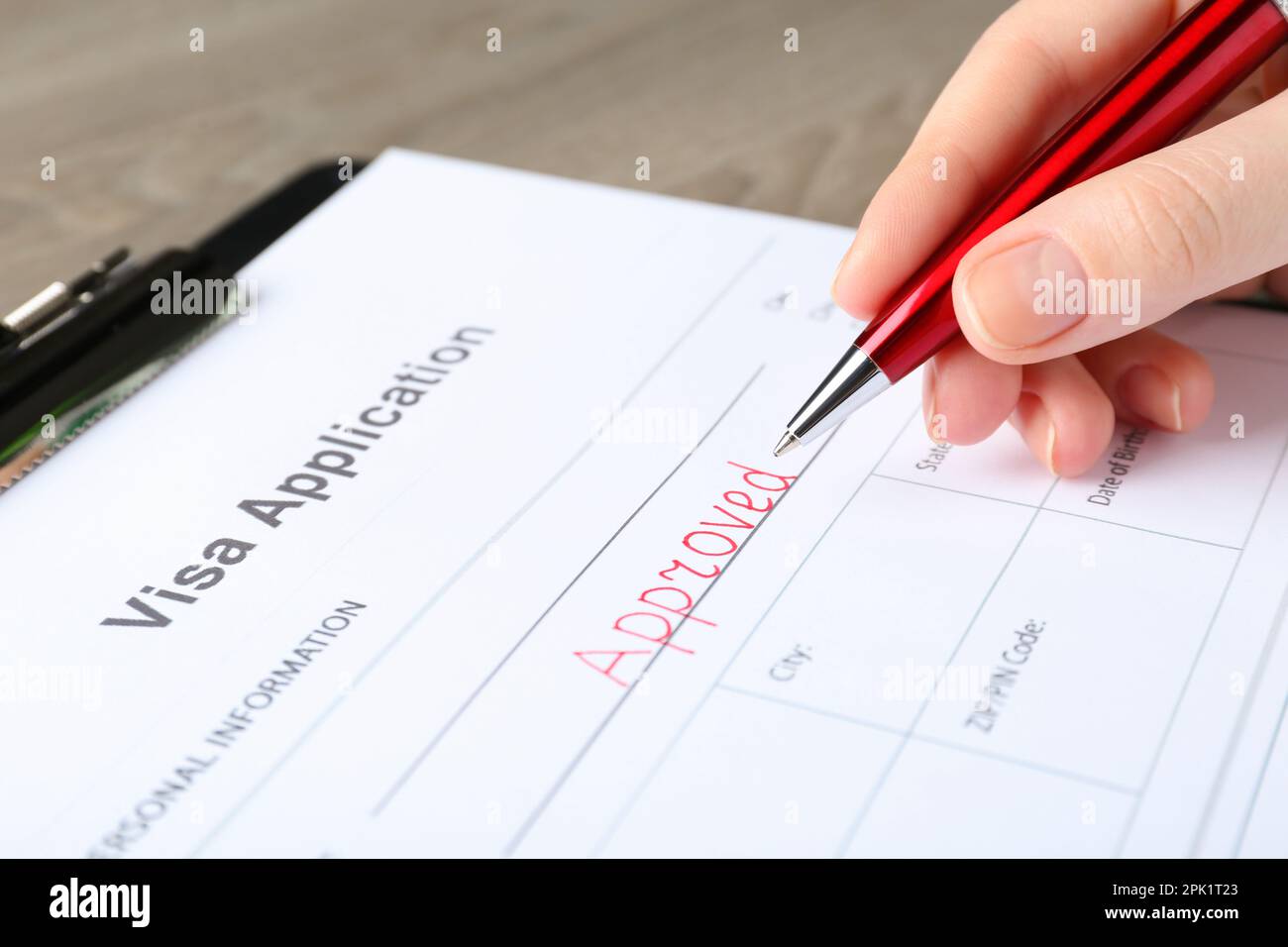 Woman writing word Approved on visa application form at table, closeup ...