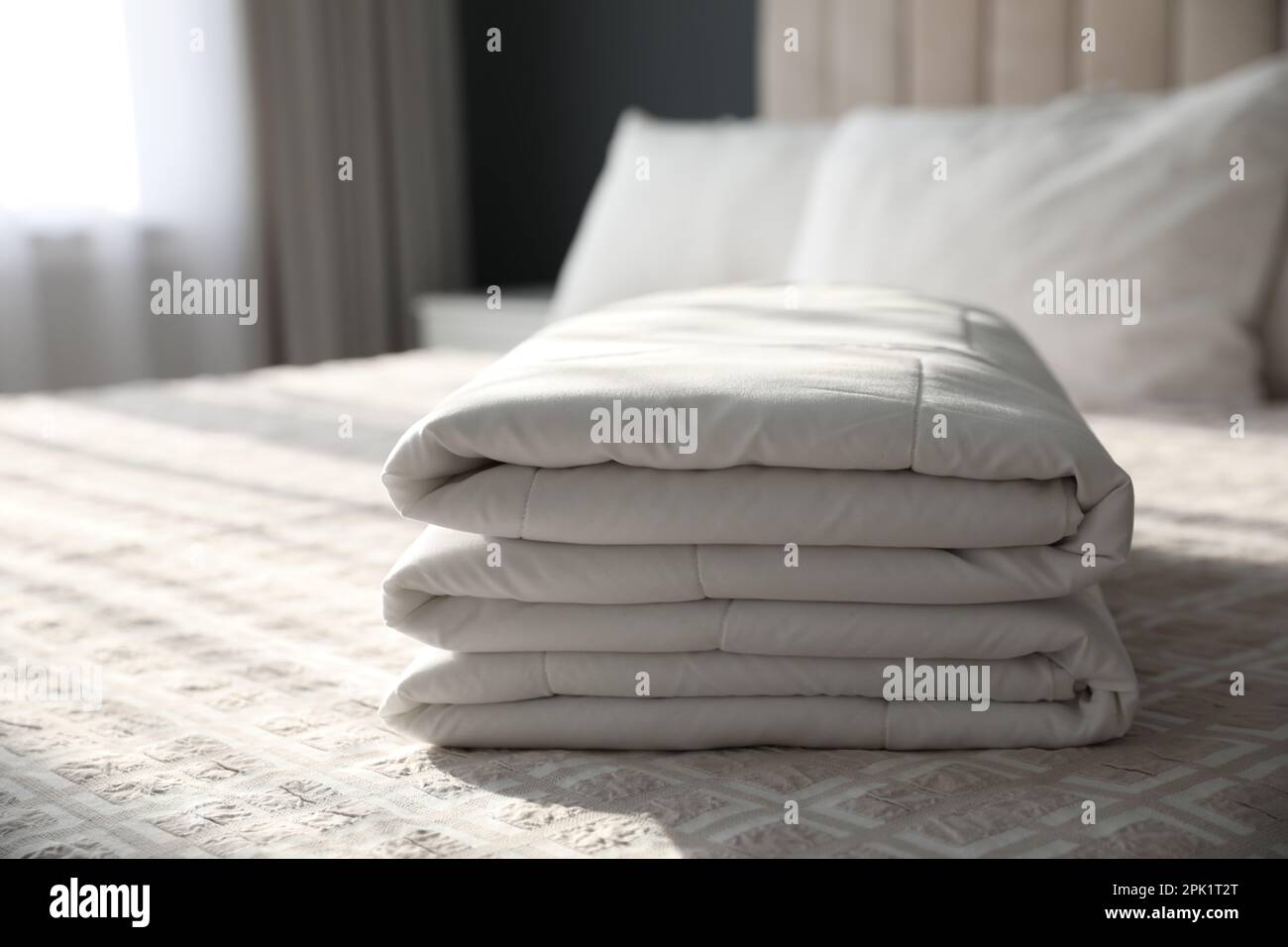 Folded clean blanket on bed in room Stock Photo - Alamy
