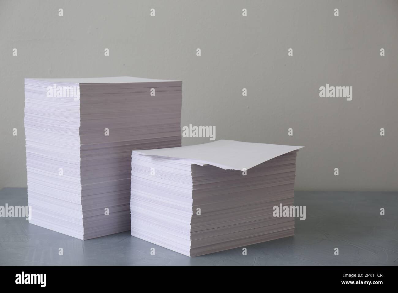 Stacks of paper sheets on grey table Stock Photo - Alamy