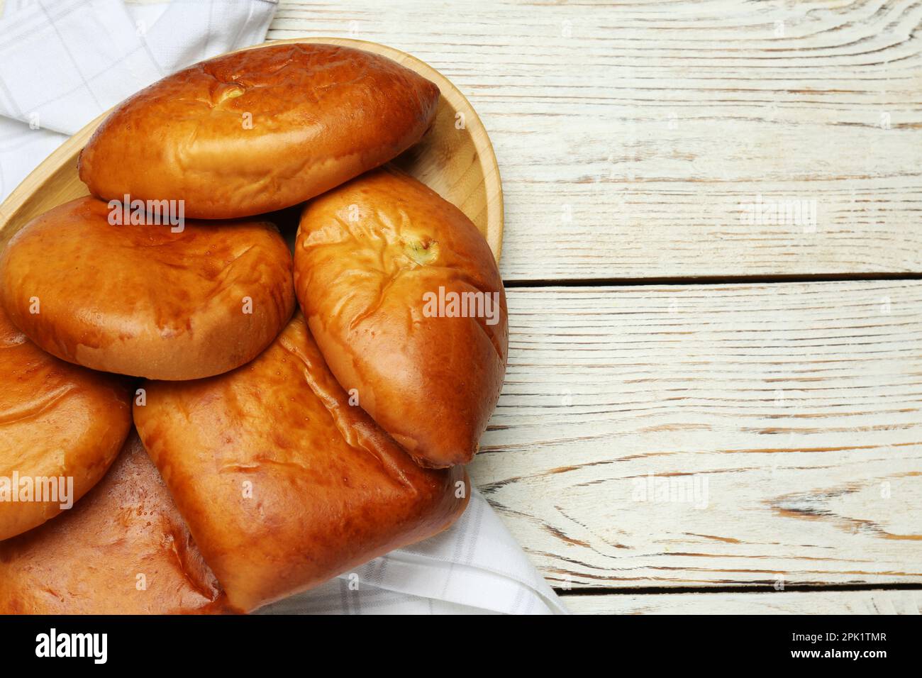 Delicious baked patties on white wooden table, top view. Space for text ...