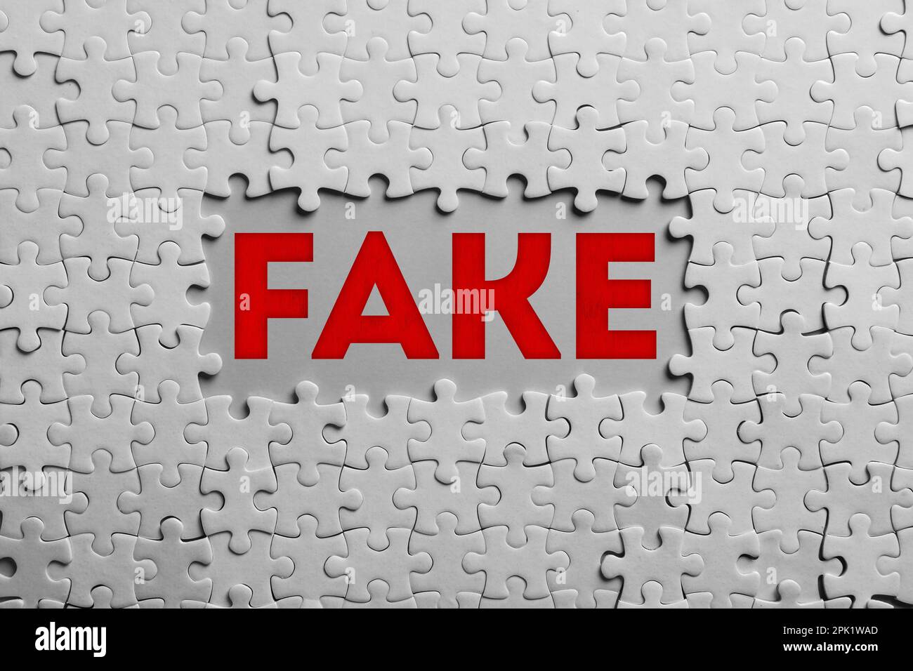 Puzzle pieces and word FAKE written on light grey background, flat lay ...