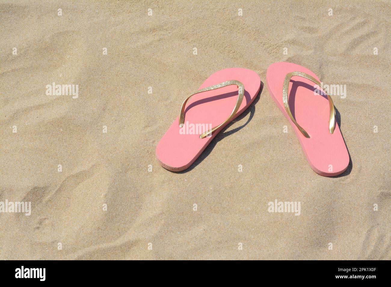 Stylish pink flip flops on sand, space for text Stock Photo - Alamy