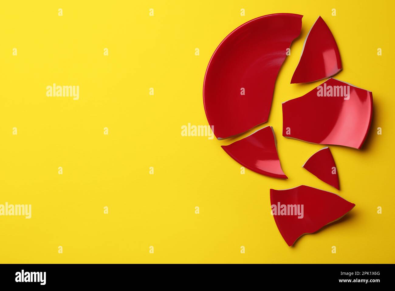 Pieces of broken red ceramic plate on yellow background, top view ...