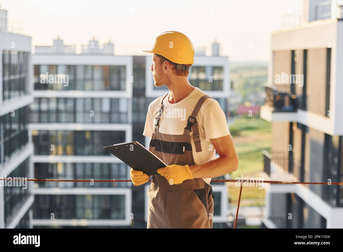 Standing high up. Young man working in uniform at construction at ...