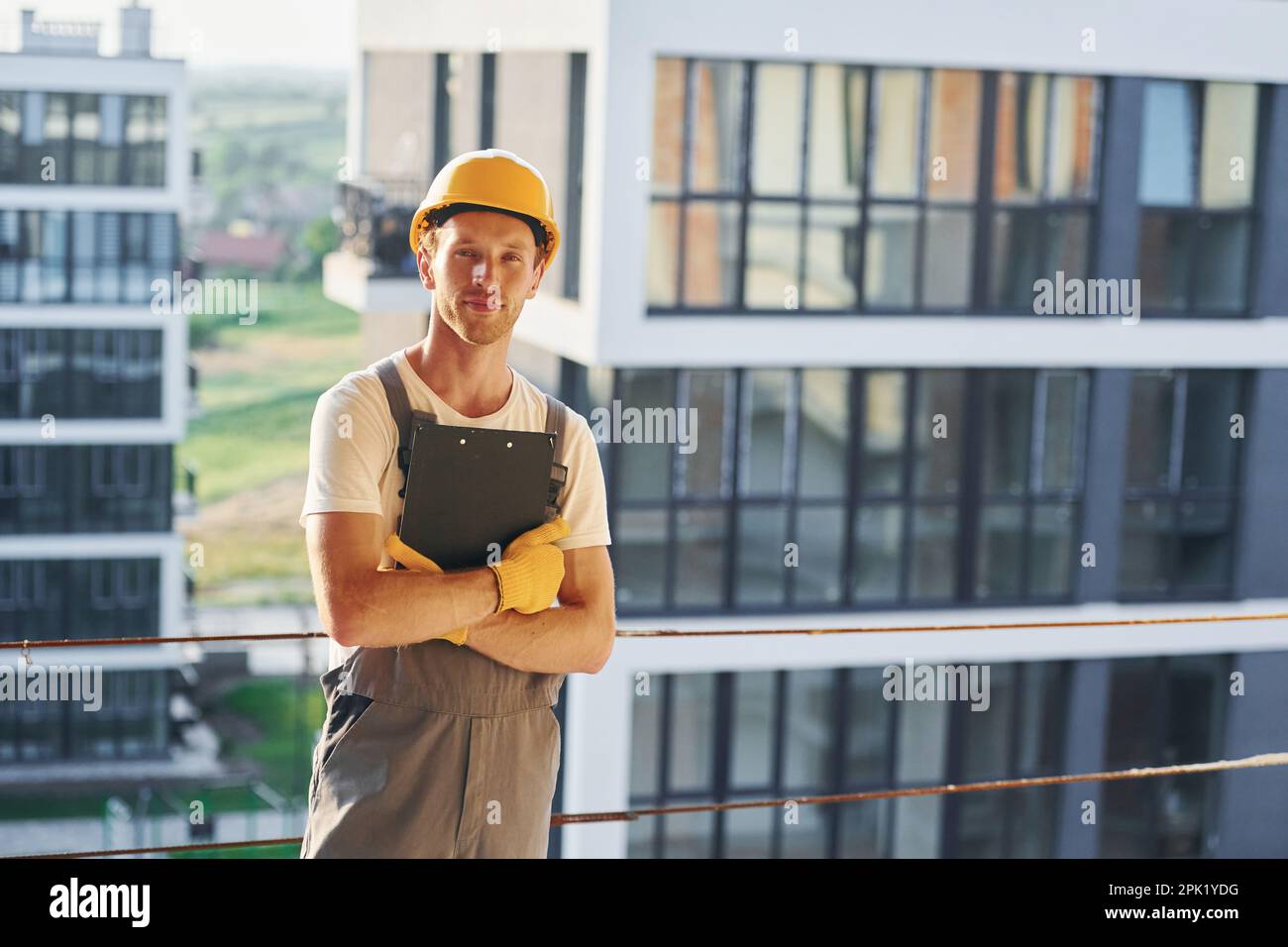 Standing high up. Young man working in uniform at construction at ...