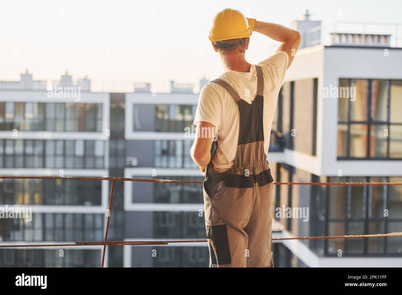 Standing high up. Young man working in uniform at construction at ...
