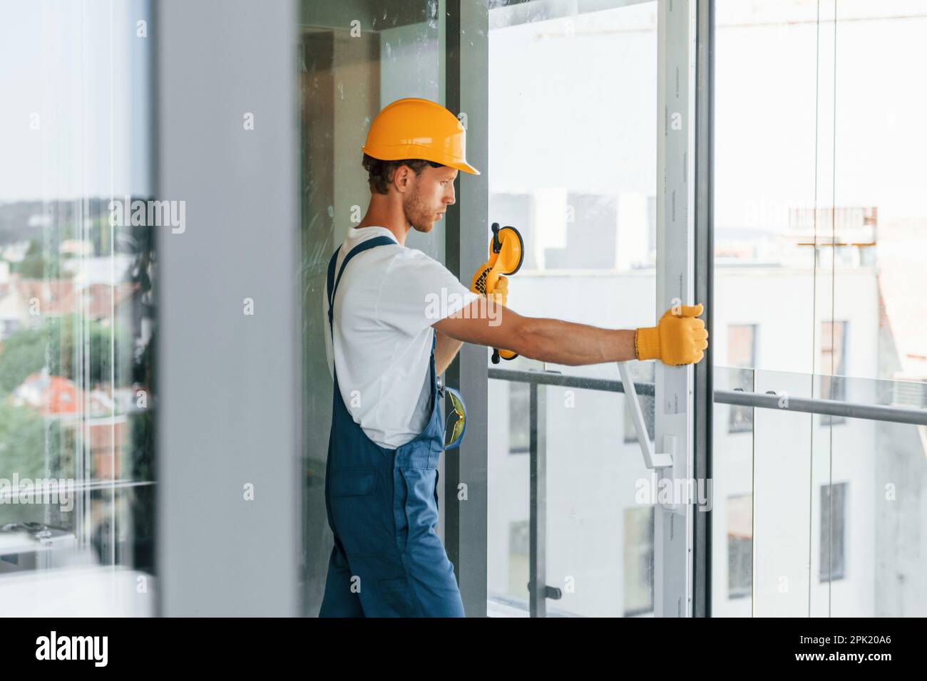Clearing windows. Young man working in uniform at construction at daytime Stock Photo - Alamy