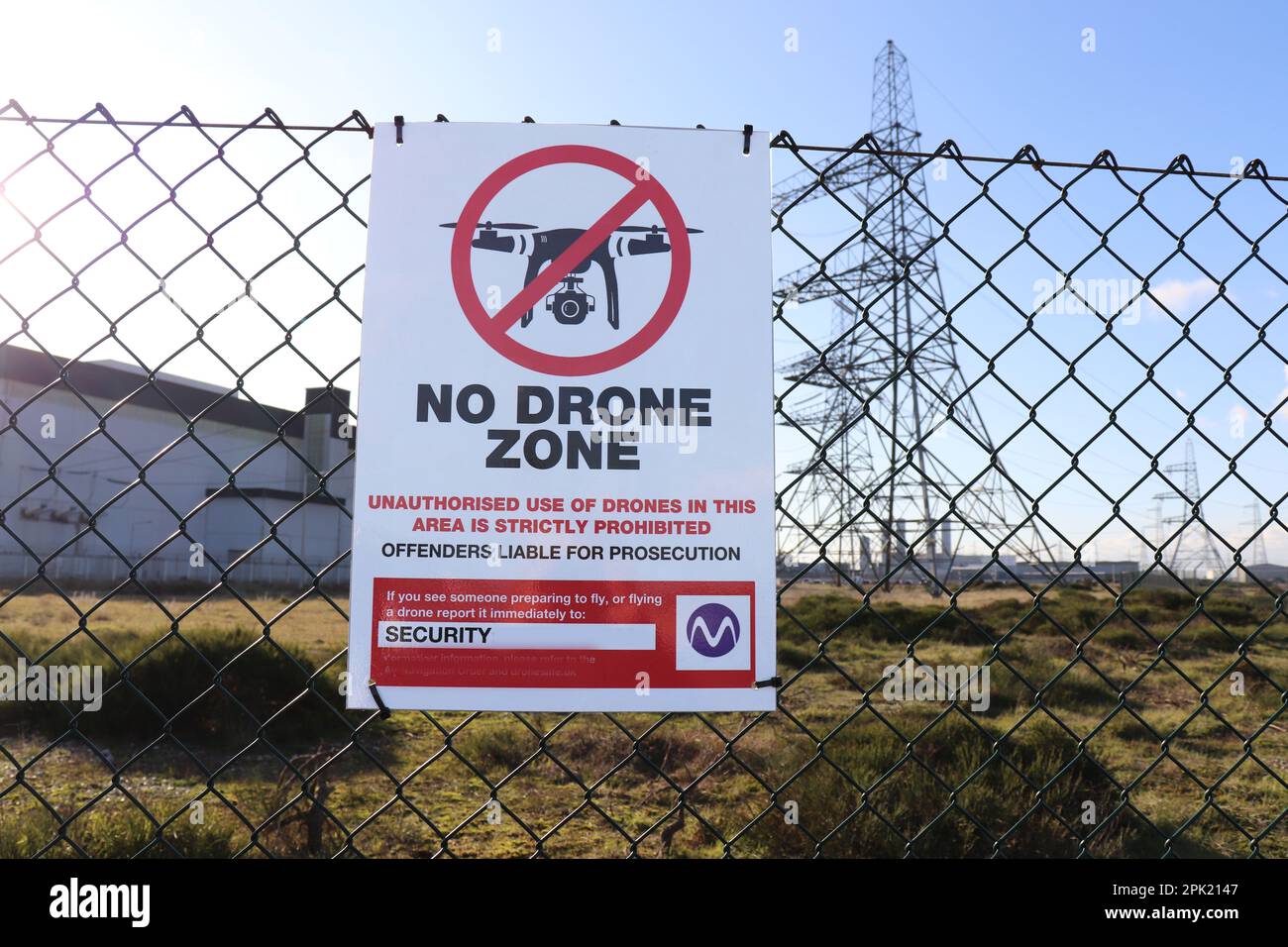 A sign saying "No Drone Zone" tied to a high metal fence. With an ...