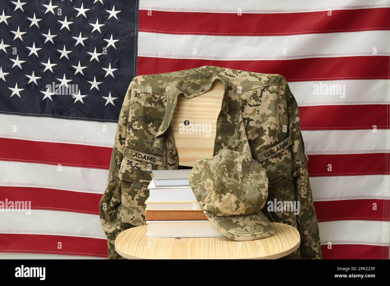 Books and soldier uniform on wooden chair near flag of United States ...