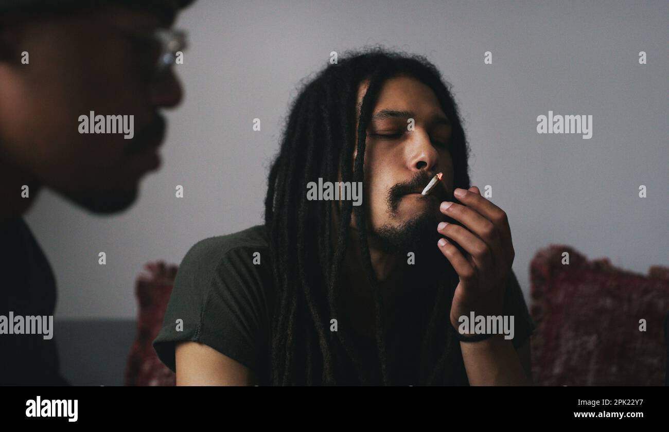 Keepin it chill. two young men smoking a marijuana joint at home Stock ...
