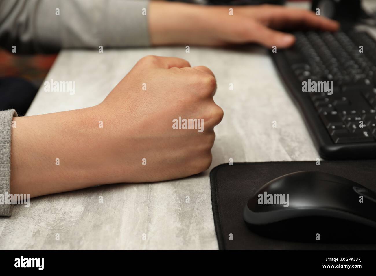 Angry man with clenched fist working on computer at table, closeup ...