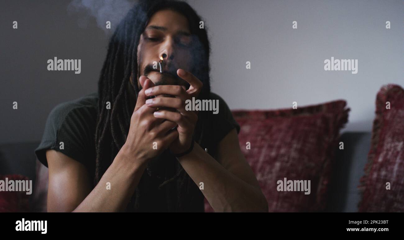 Getting lit. a young man smoking a marijuana joint at home Stock Photo ...