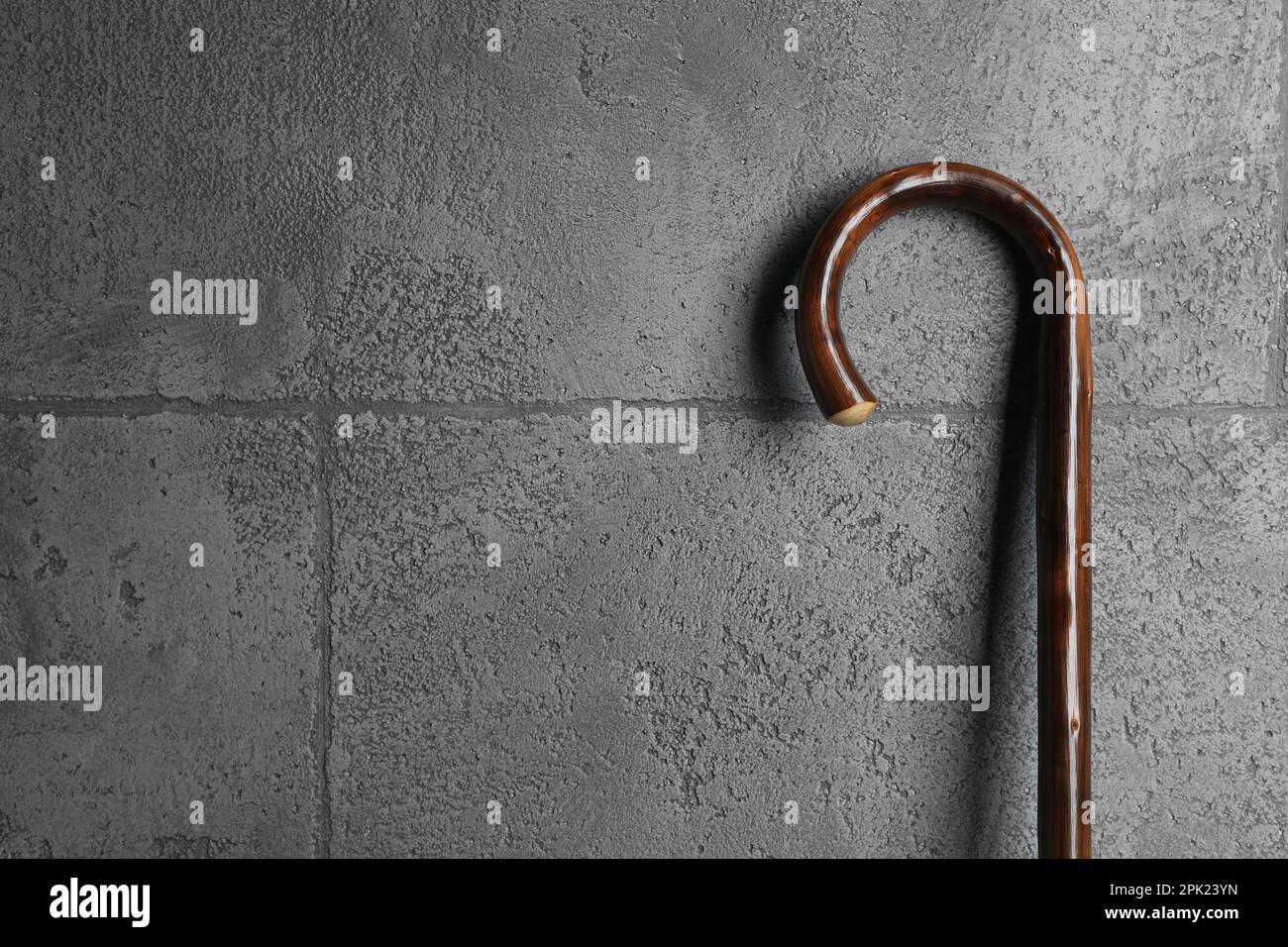 Elegant wooden walking cane on grey stone background, closeup. Space ...