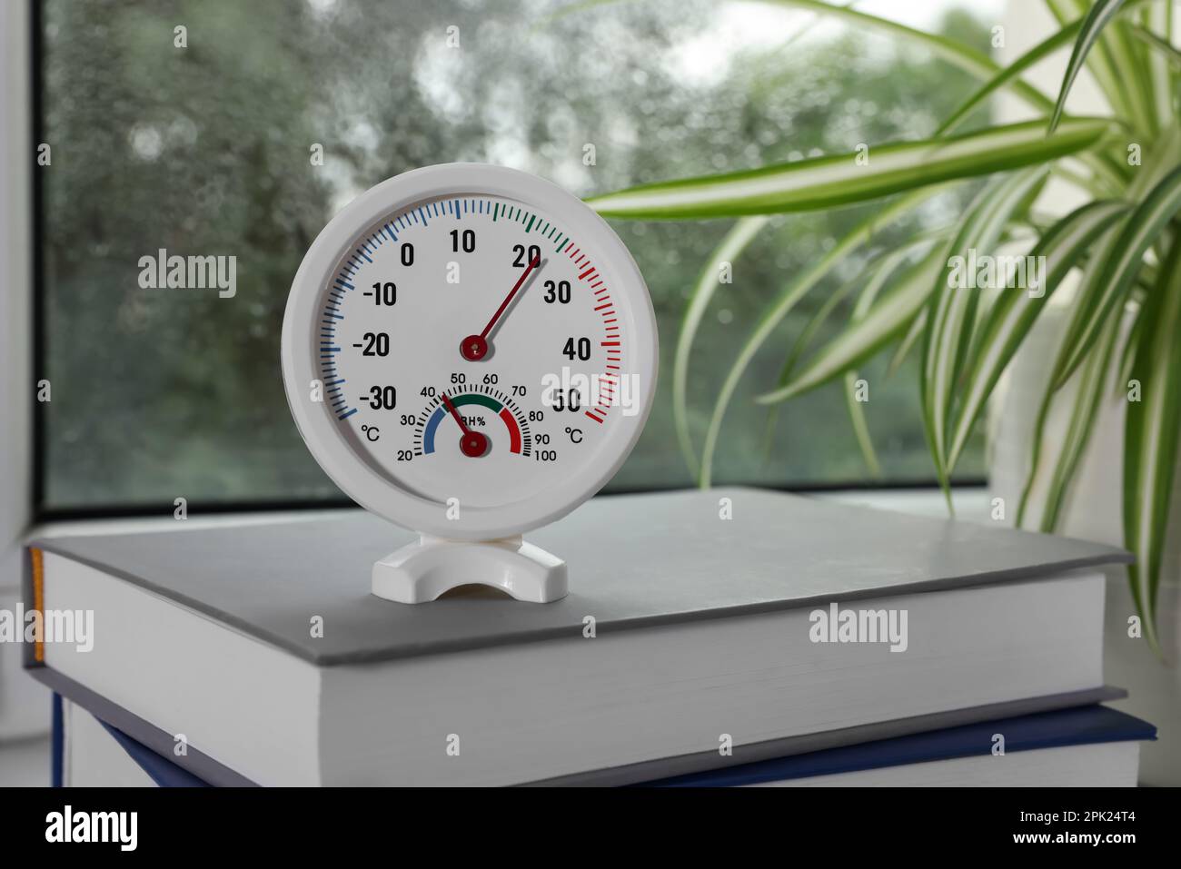 Round mechanical hygrometer on book near window Stock Photo - Alamy