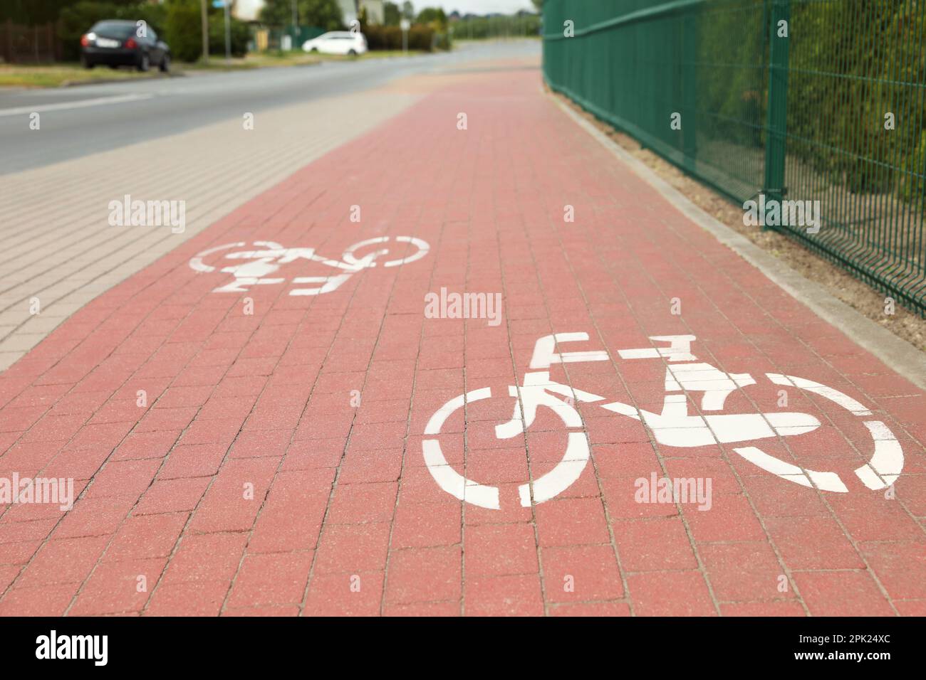 Red bicycle lane with white signs on pavement along road Stock Photo ...