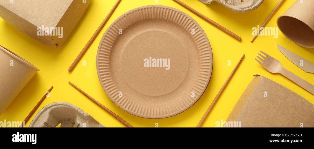Paper and wooden tableware on yellow background, flat lay. Banner ...