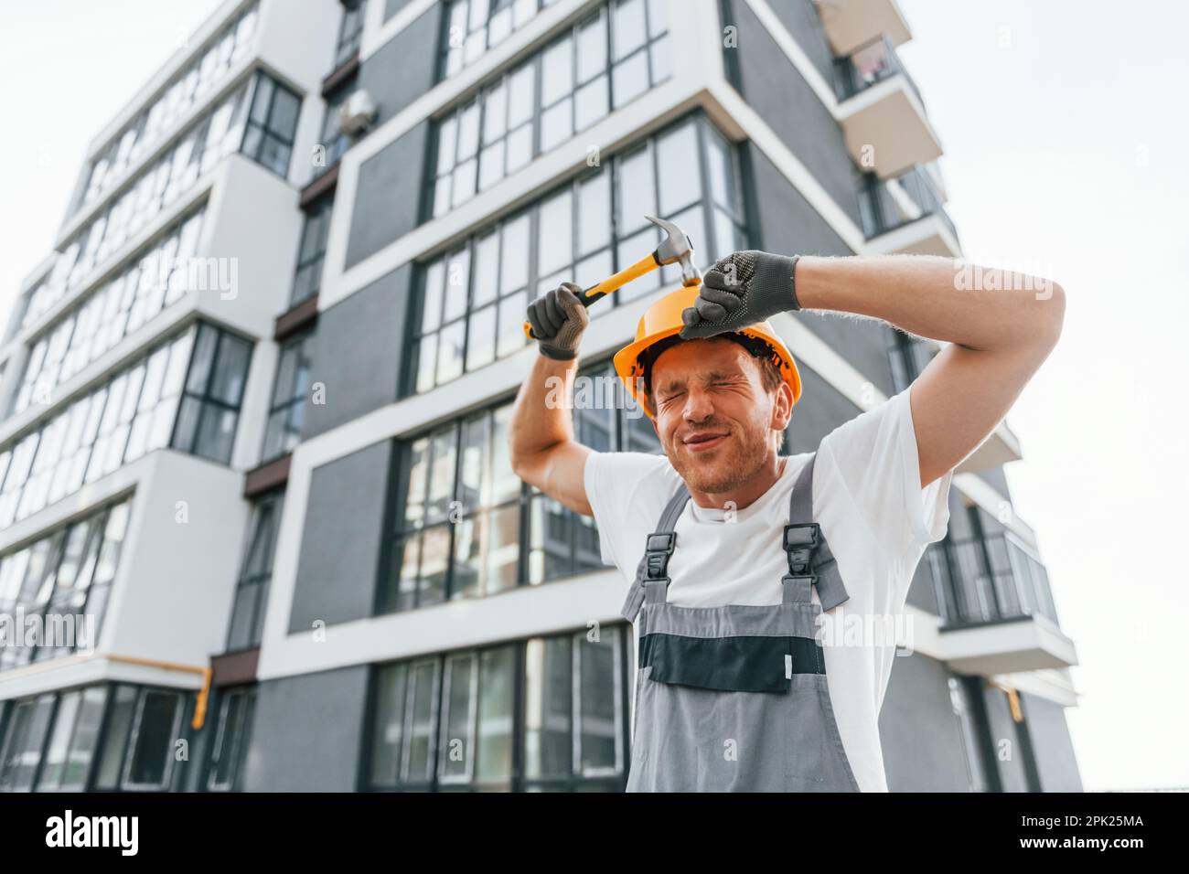Standing near modern buildings. Young man working in uniform at ...