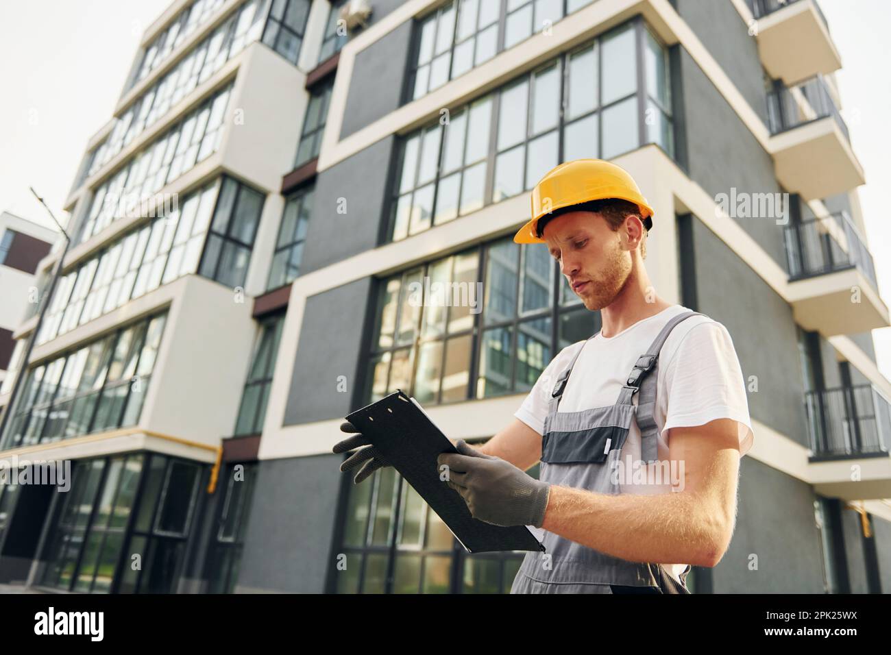 Modern city. Young man working in uniform at construction at daytime ...