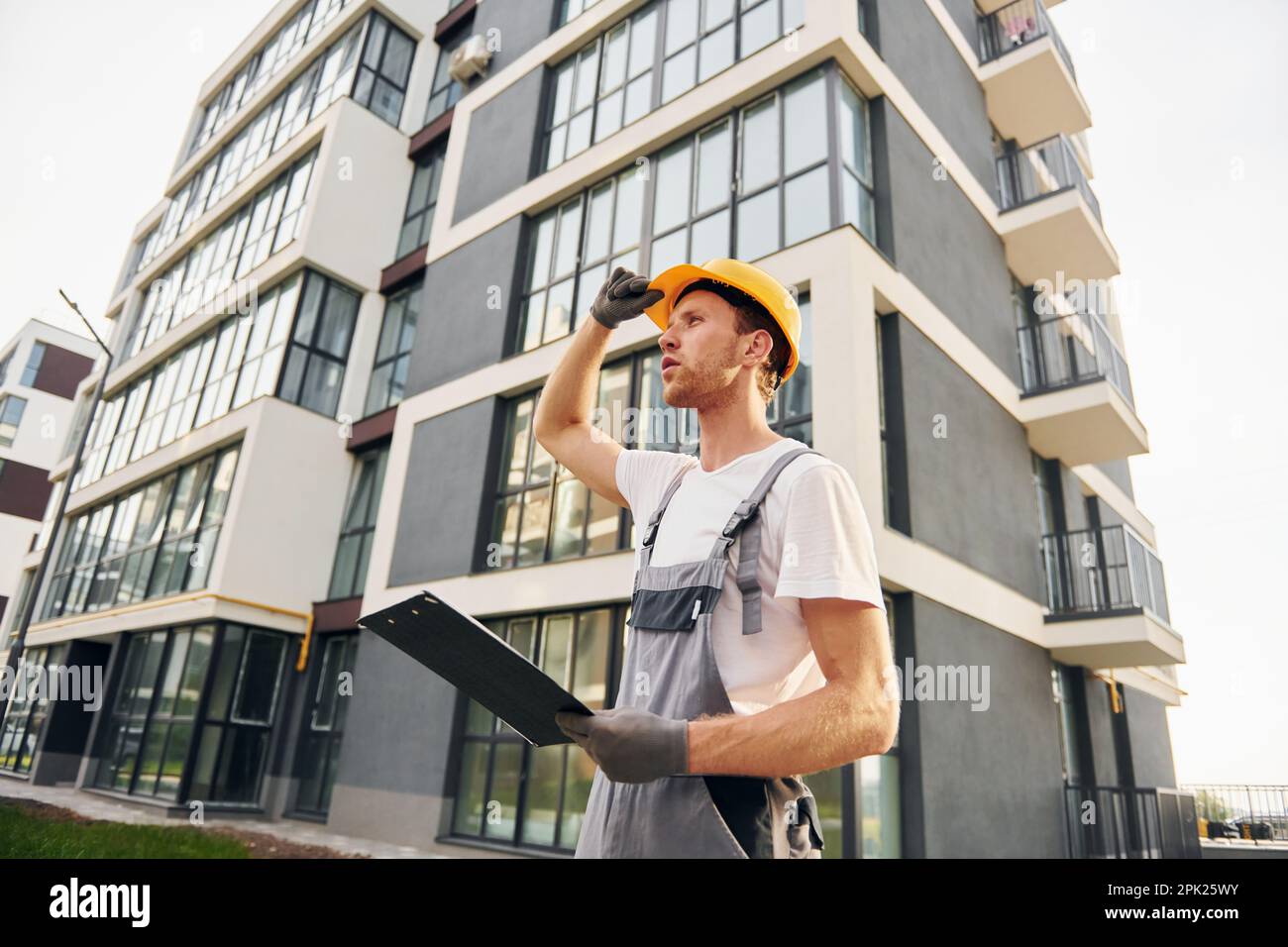 Modern city. Young man working in uniform at construction at daytime ...